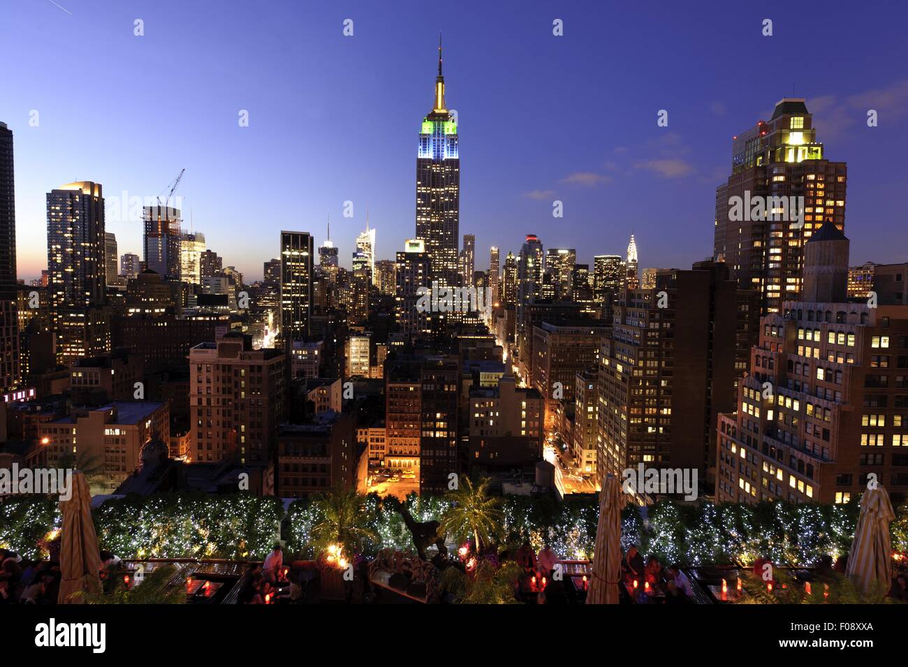 View of cityscape overlooking people sitting on rooftop bar at New York ...