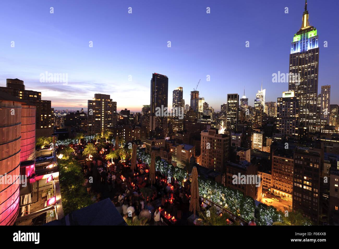 View of cityscape overlooking people sitting on rooftop bar at New York ...