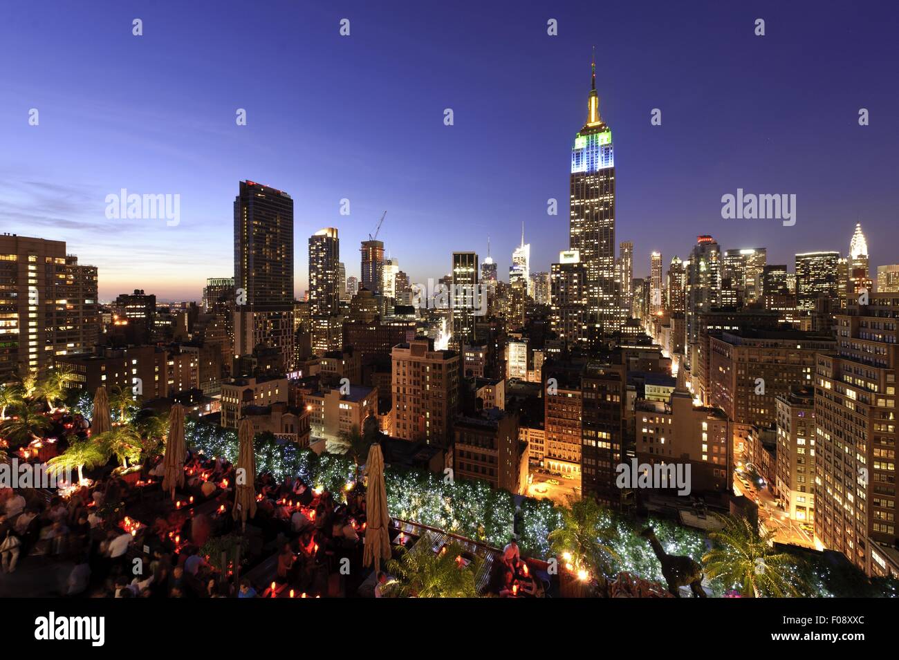 View of cityscape overlooking people sitting on rooftop bar at New York ...