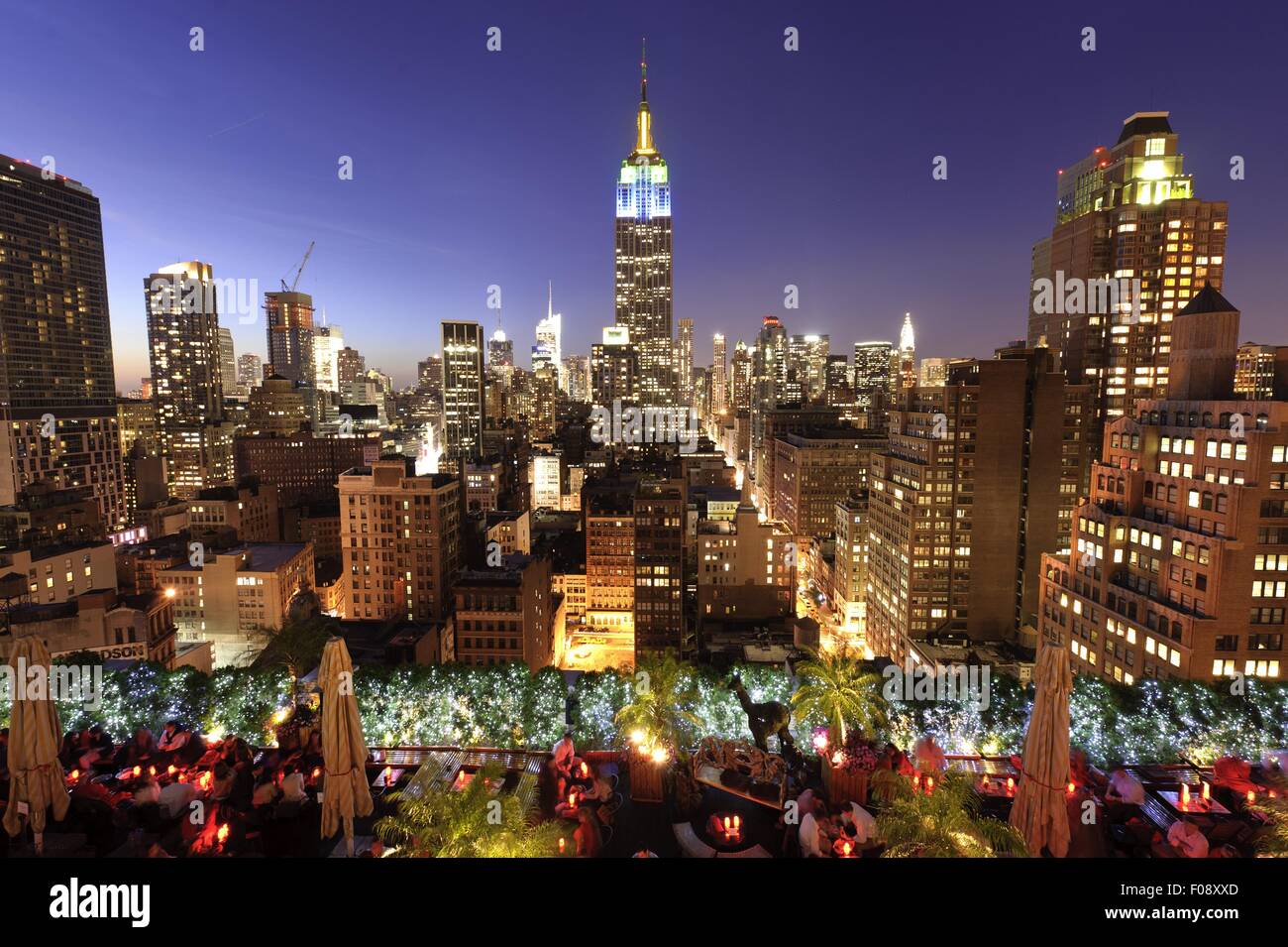 View of cityscape overlooking people sitting on rooftop bar at New York ...