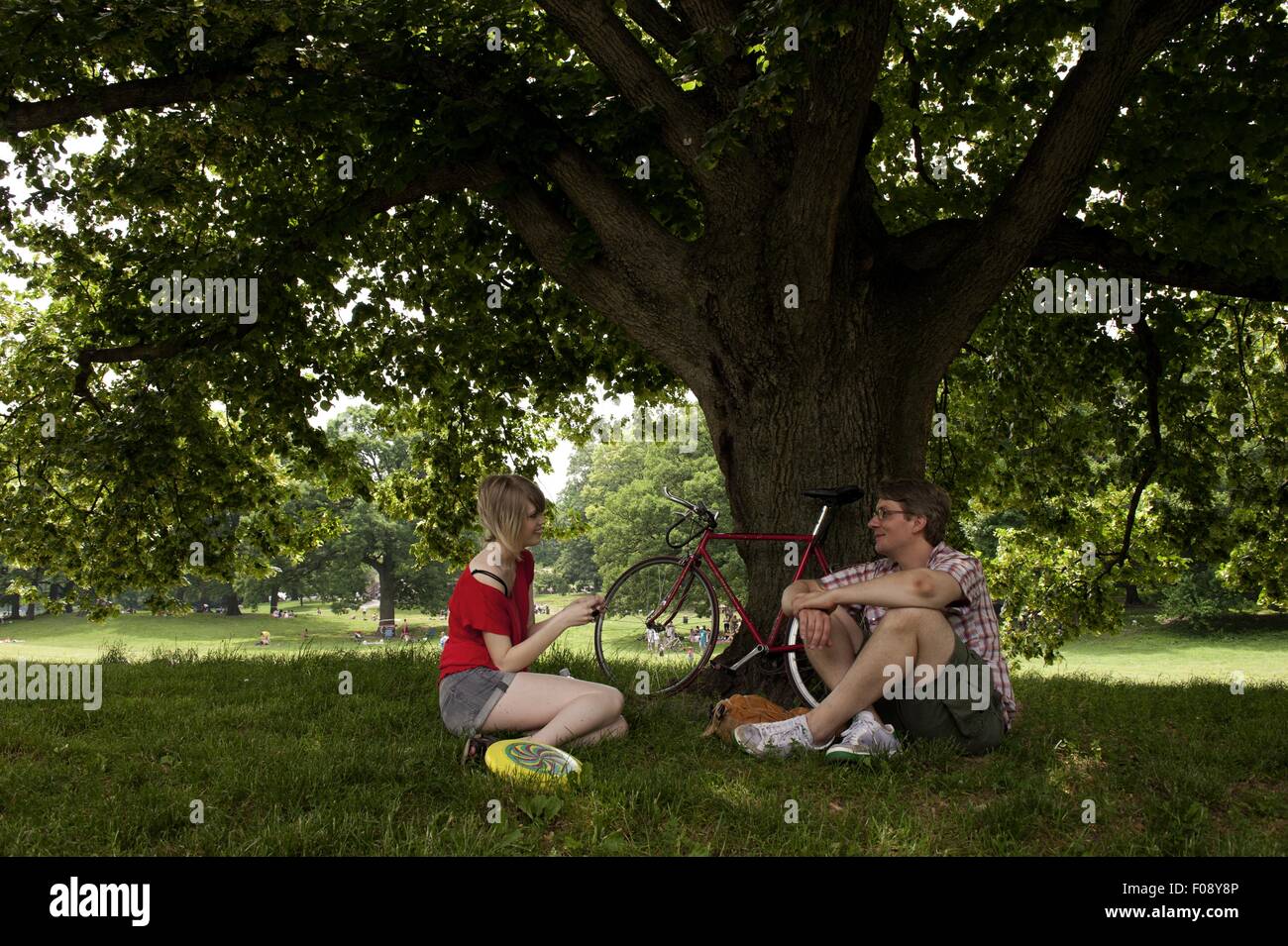 Couple sitting and relaxing under tree at park in New York, USA Stock ...