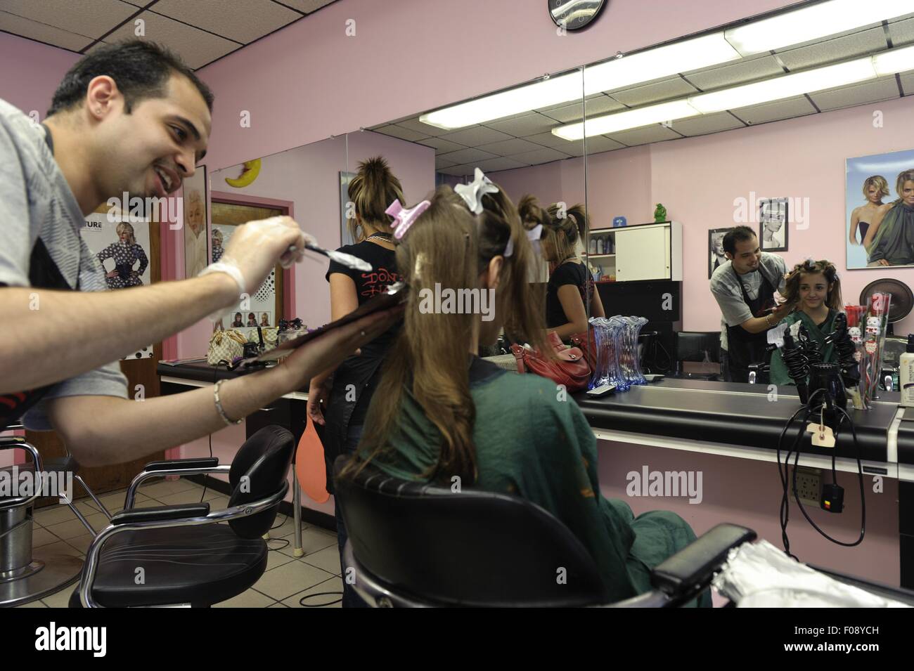 Hairdresser applying colour to woman's hair at a salon in Bronx, New ...