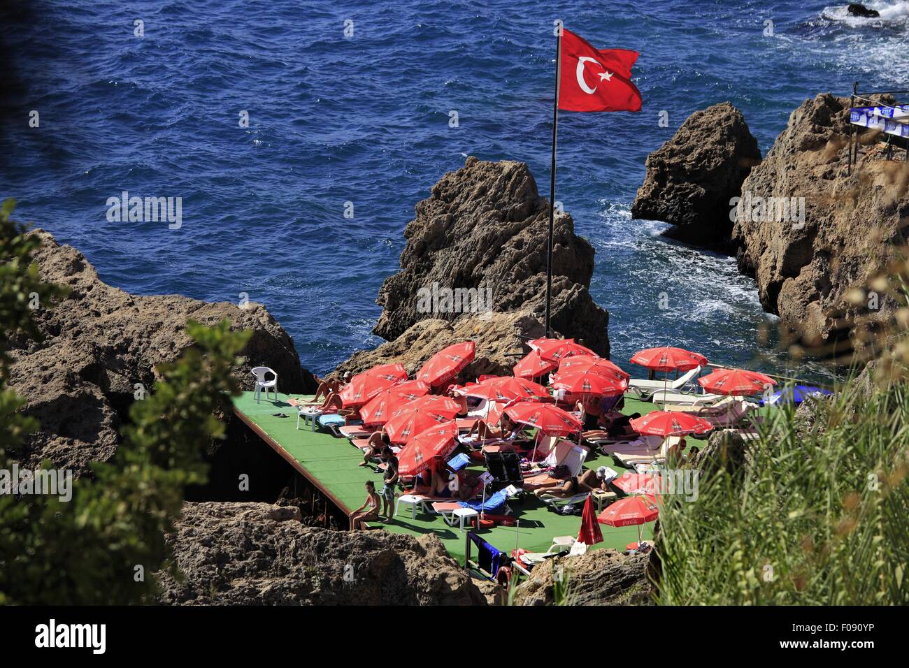 Turkish flag and people relaxing on sun loungers near sea in Antalya ...