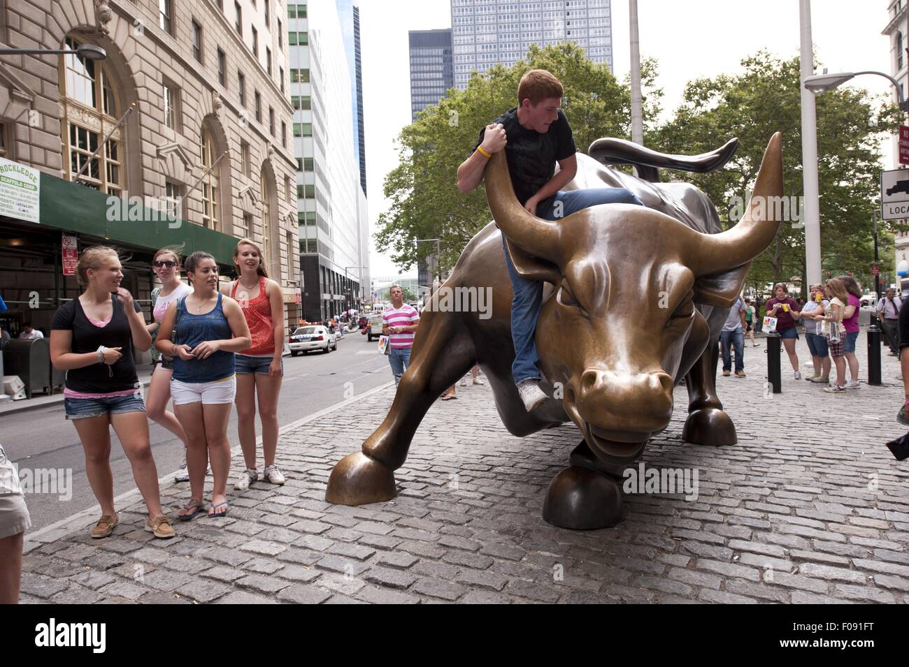 Women watching man sitting on Charging Bull at Bowling Green Park, New ...