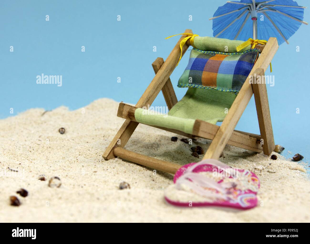 Beach chair with flip flops and umbrella on sand Stock Photo - Alamy