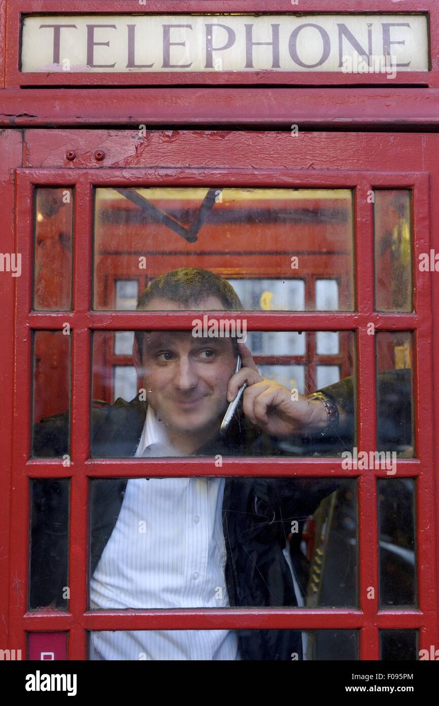Man talking on phone inside telephone booth in Aldwych, London, UK ...