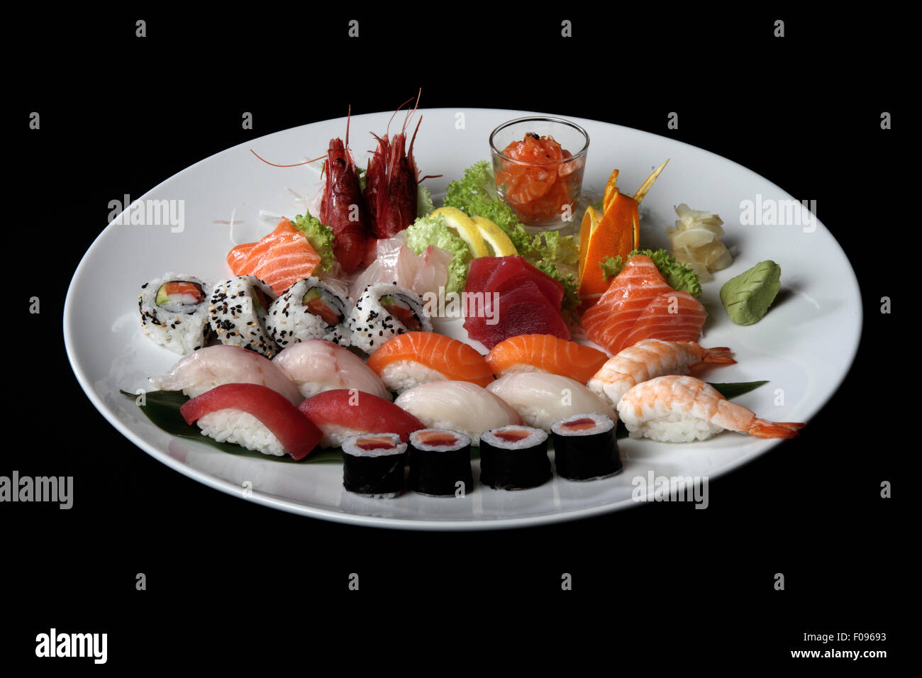 round plate of sushi and sashimi on black background Stock Photo - Alamy