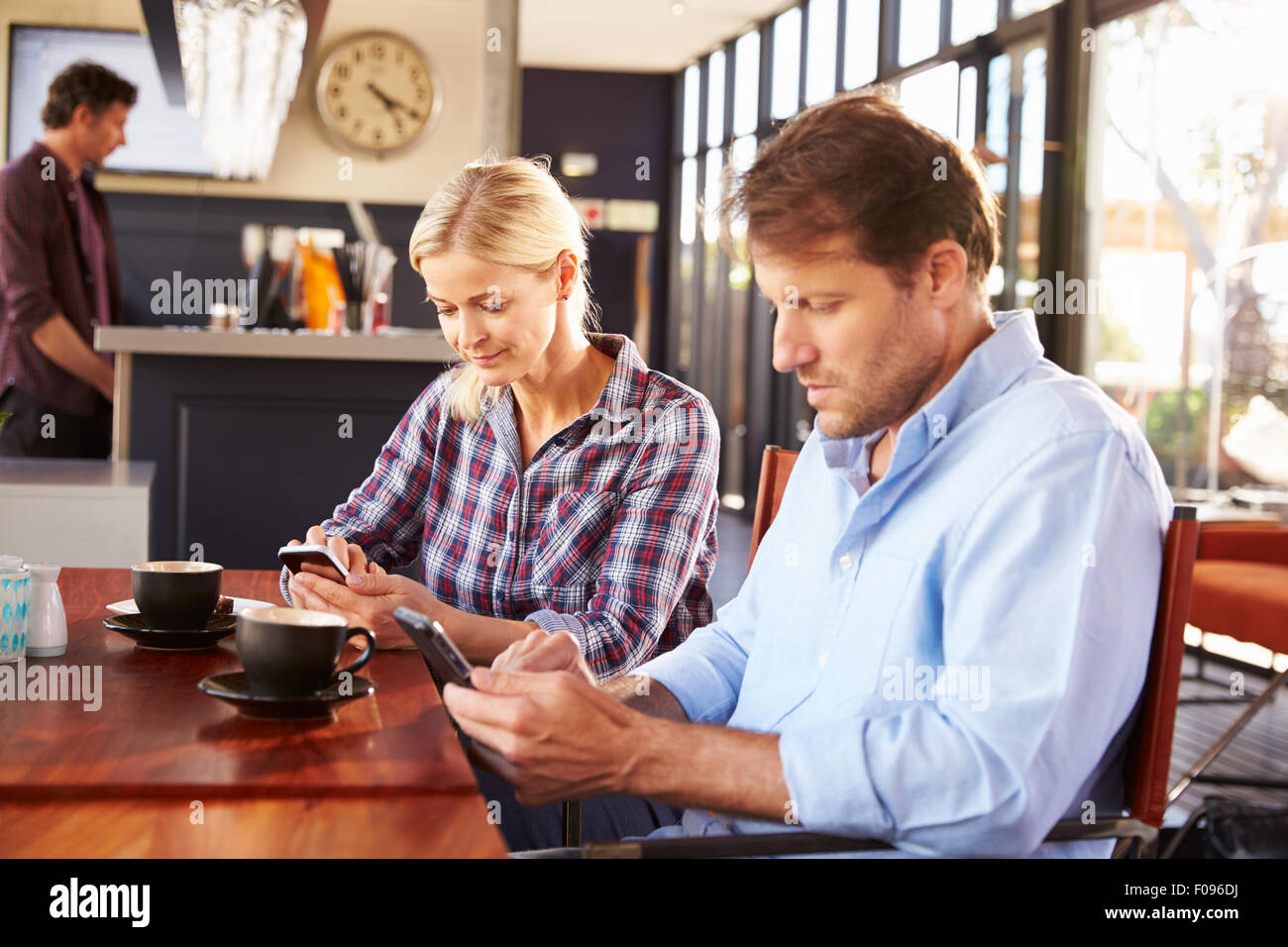 Man and woman using smart phones at coffee shop Stock Photo - Alamy