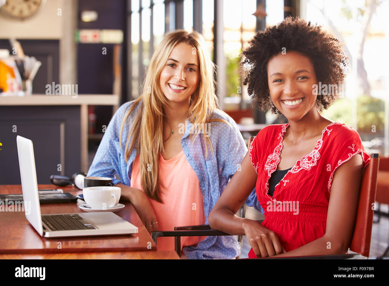 Two women with computer in a coffee shop, portrait Stock Photo - Alamy
