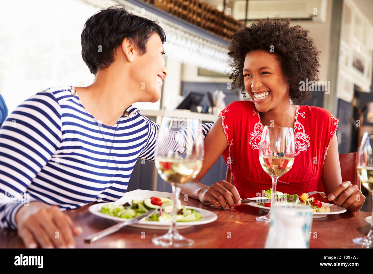 Two female friends eating at a restaurant Stock Photo - Alamy