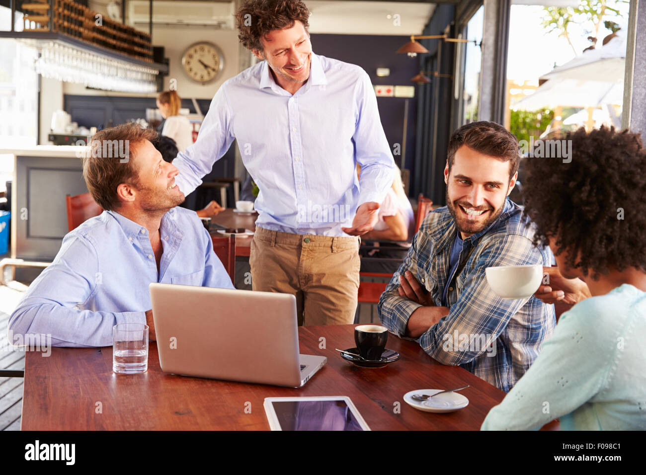 Restaurant manager talking to customers at their table Stock Photo - Alamy
