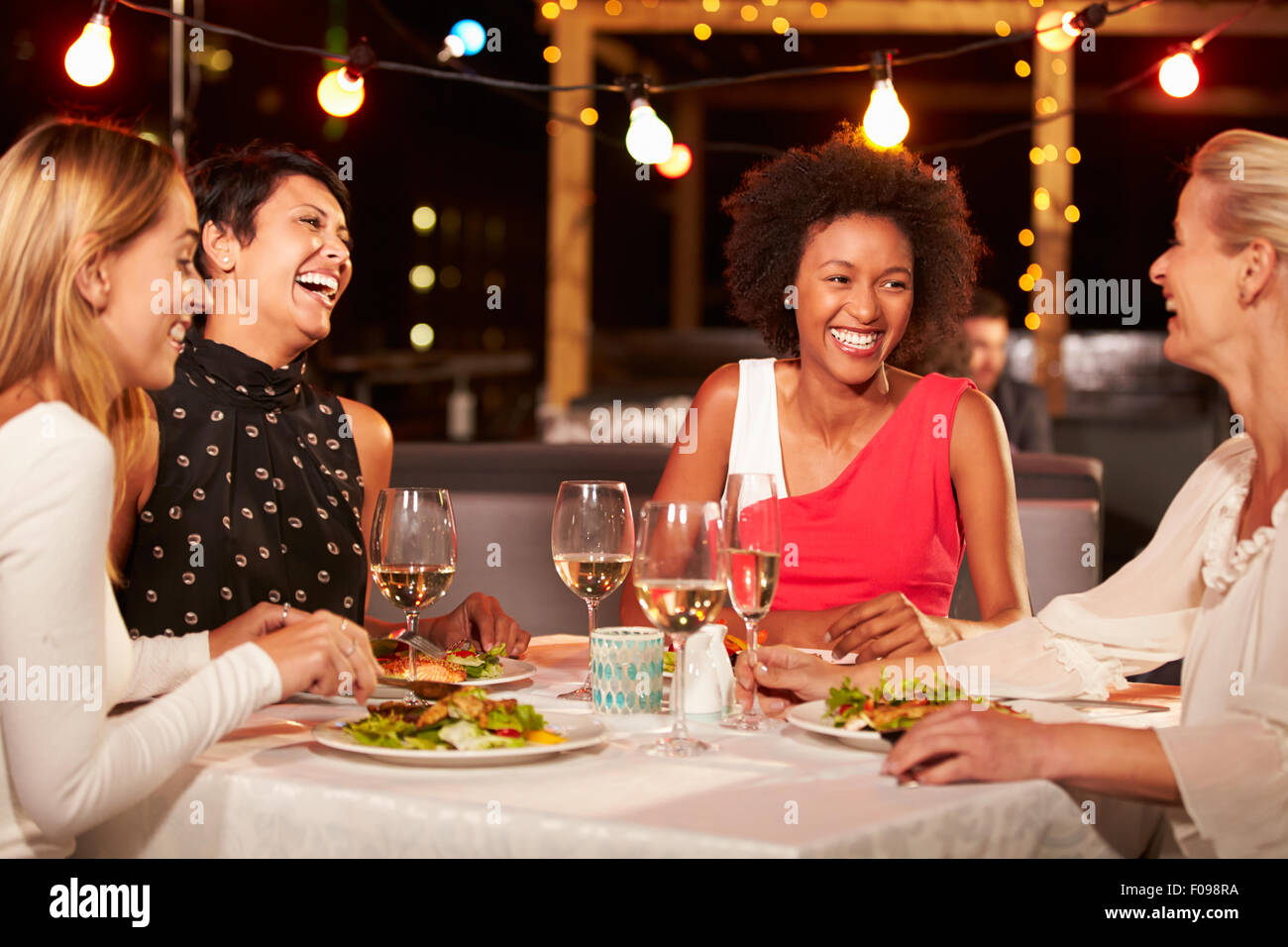Group of female friends eating dinner at rooftop restaurant Stock Photo ...