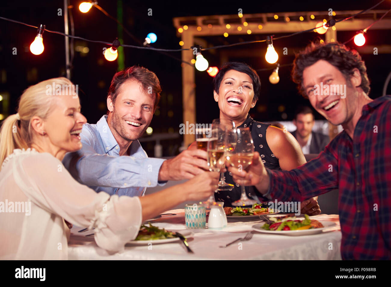 Group of friends eating dinner at rooftop restaurant Stock Photo - Alamy