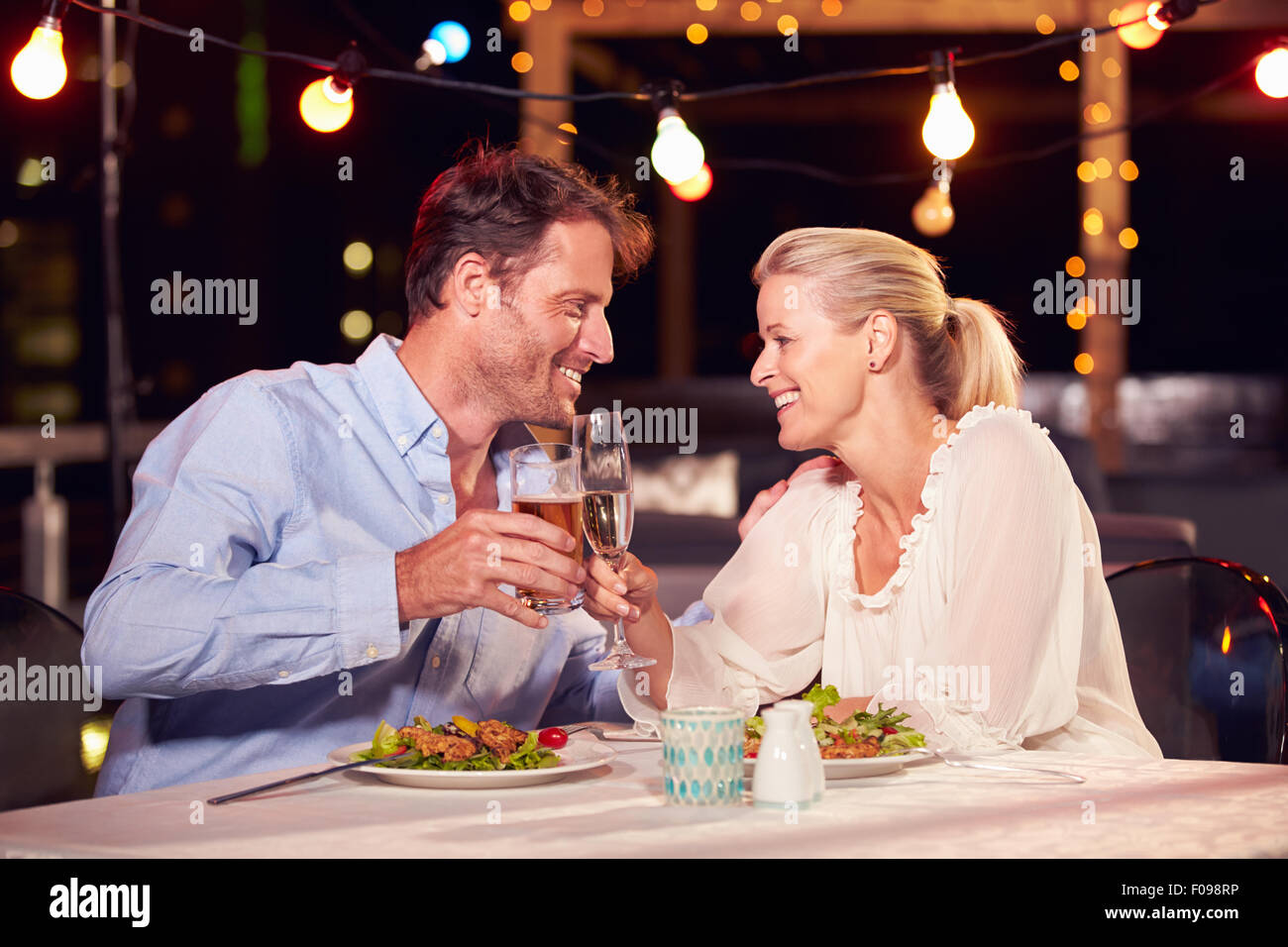 Couple eating dinner at rooftop restuarant Stock Photo - Alamy