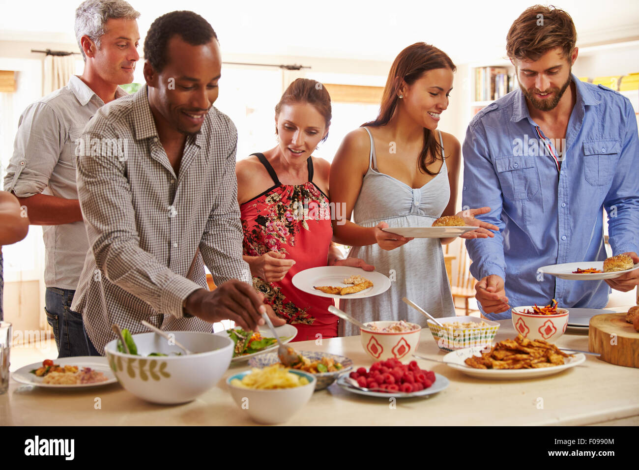 Friends serving themselves food and talking at dinner party Stock Photo ...