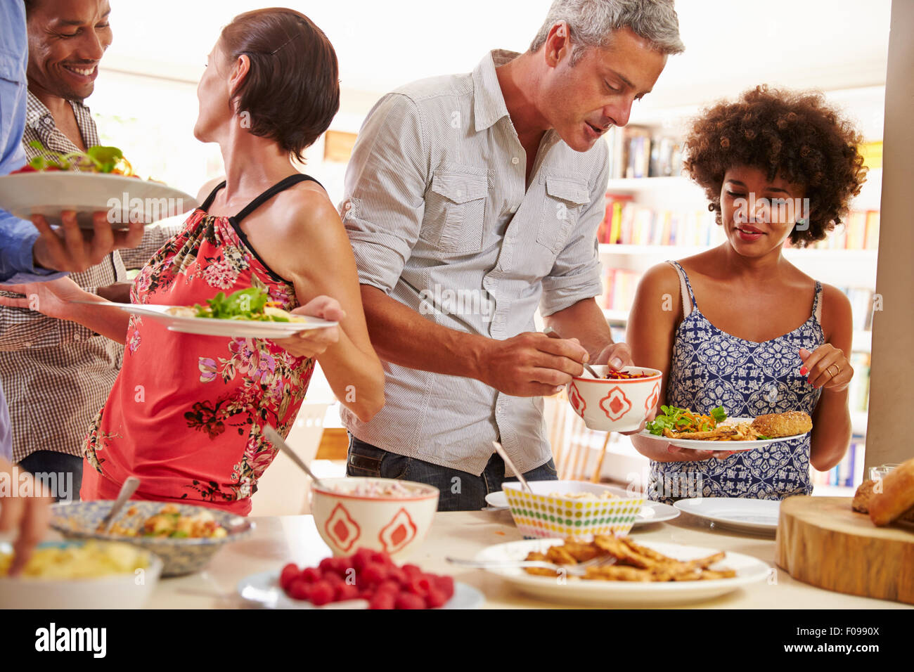 Friends serving themselves food and talking at dinner party Stock Photo ...