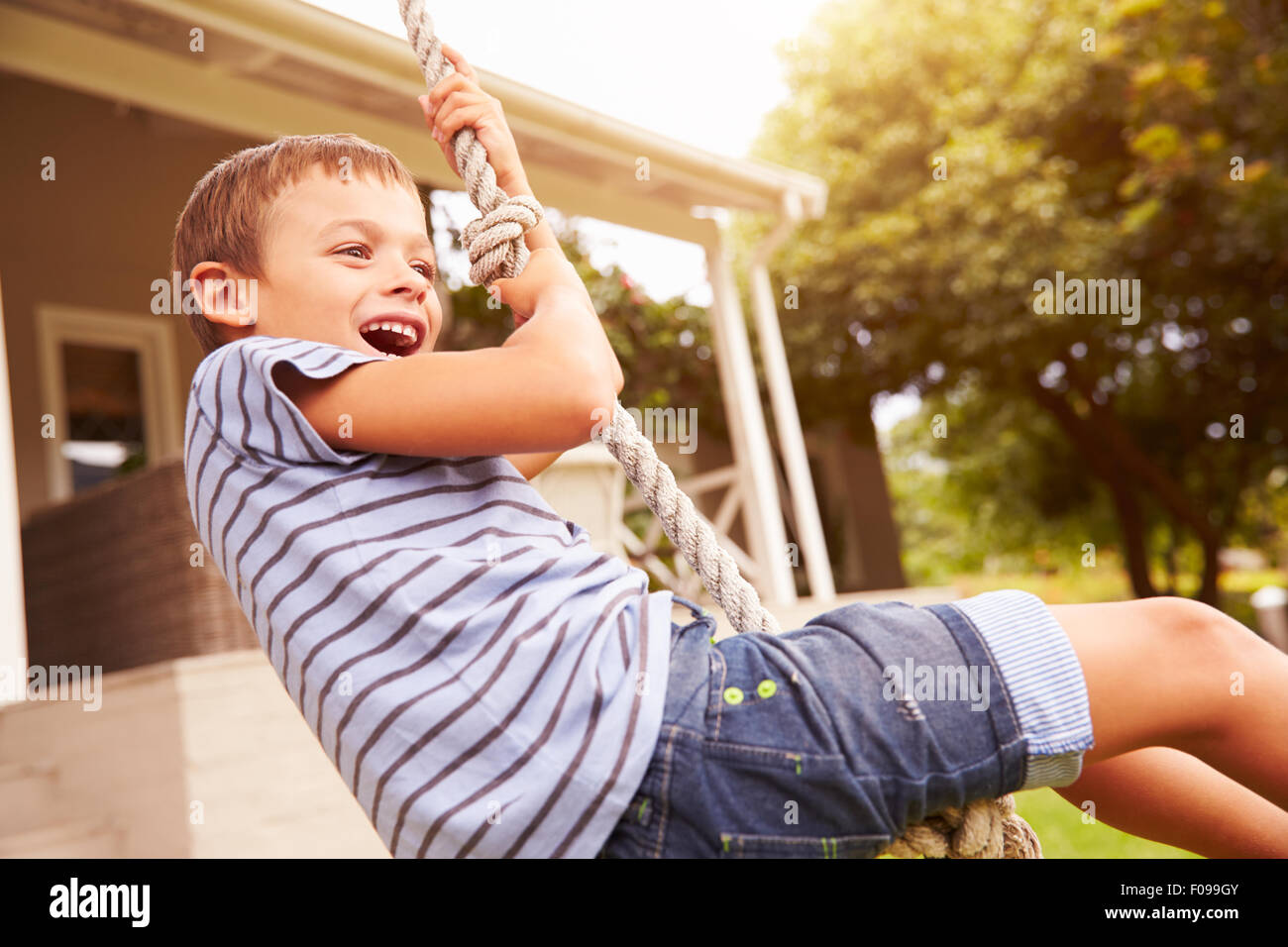 Smiling boy swinging on a rope at a playground Stock Photo - Alamy