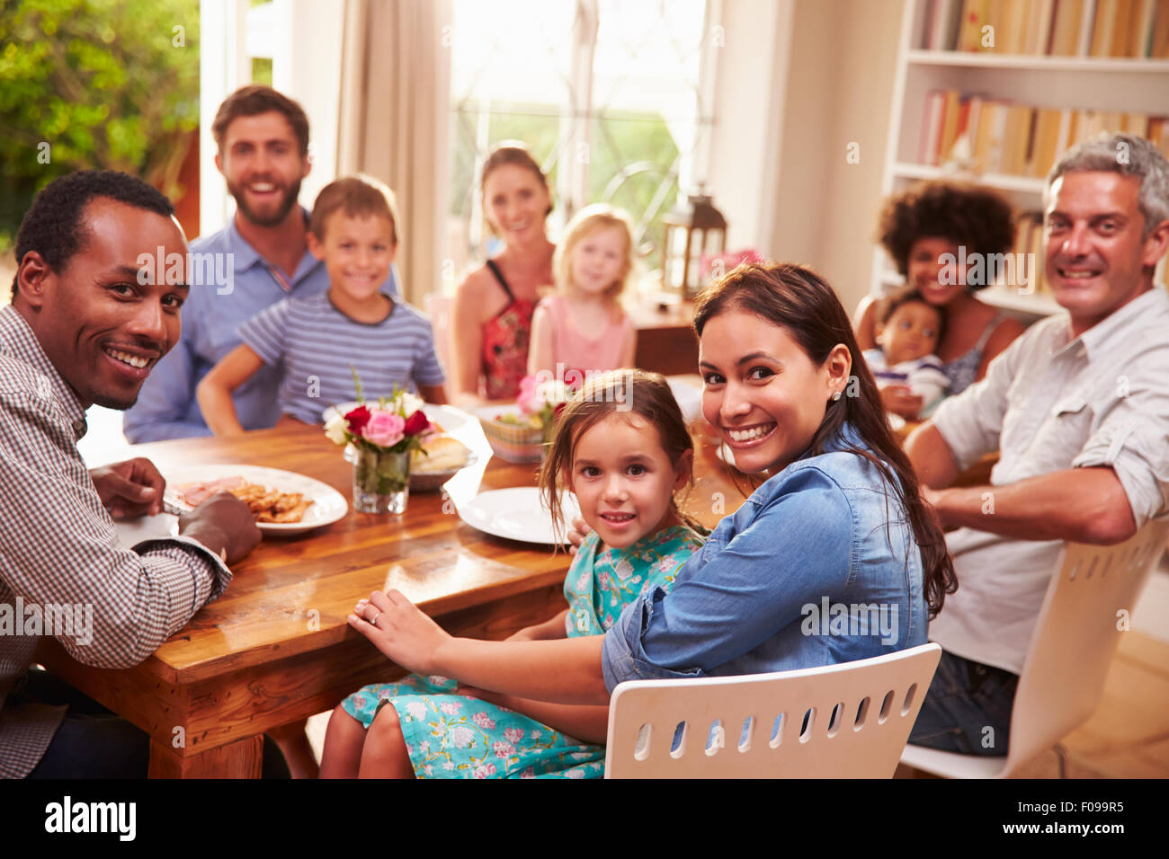 Family and friends sitting at a dining table, looking at camera Stock ...