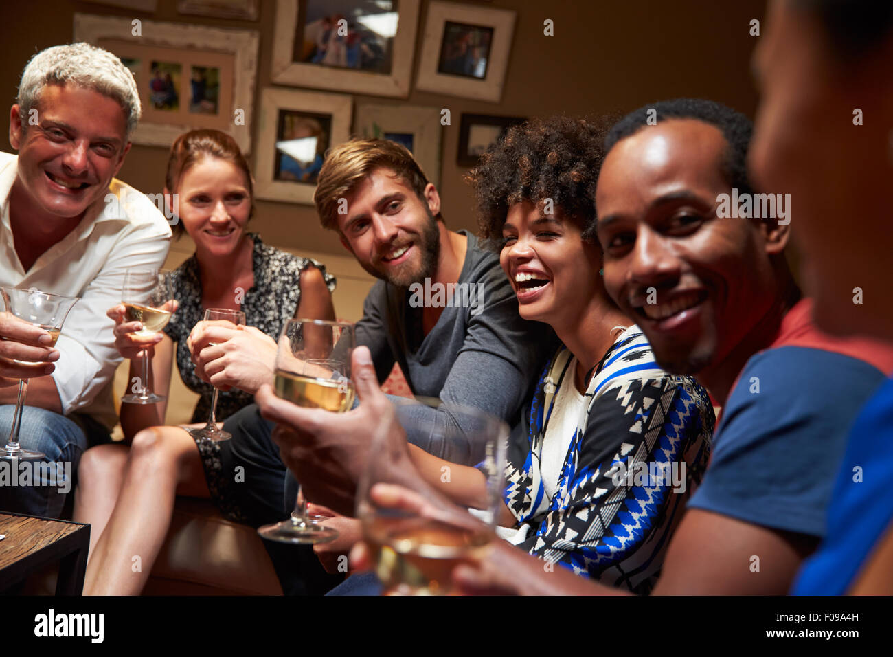 Group of friends sitting around a table at house party Stock Photo - Alamy