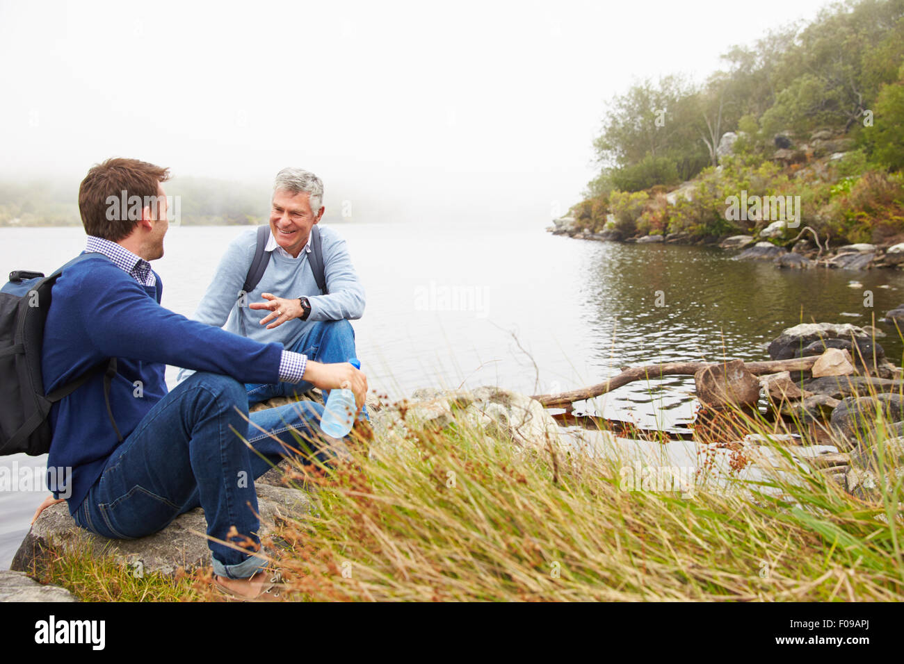 Father and young adult son talking by a lake Stock Photo - Alamy