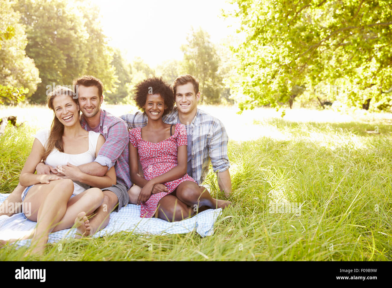 Two couples relaxing together in the countryside Stock Photo - Alamy
