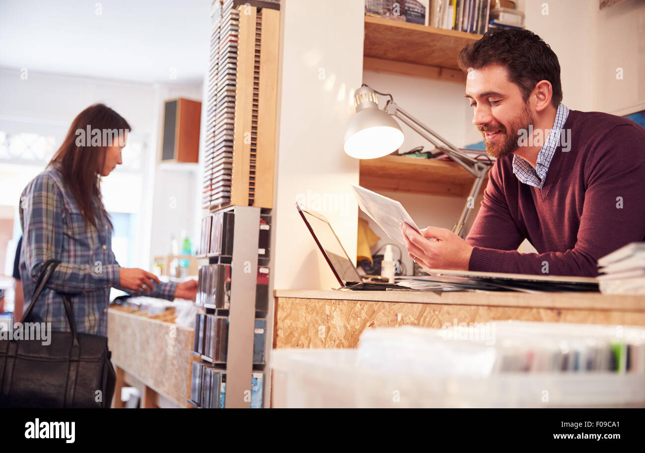 Man working behind the counter at a record shop Stock Photo - Alamy