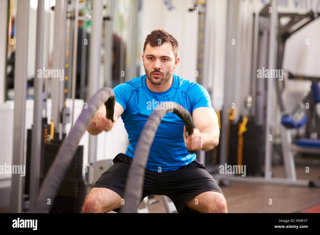 Young man working out with battle ropes at a gym Stock Photo - Alamy
