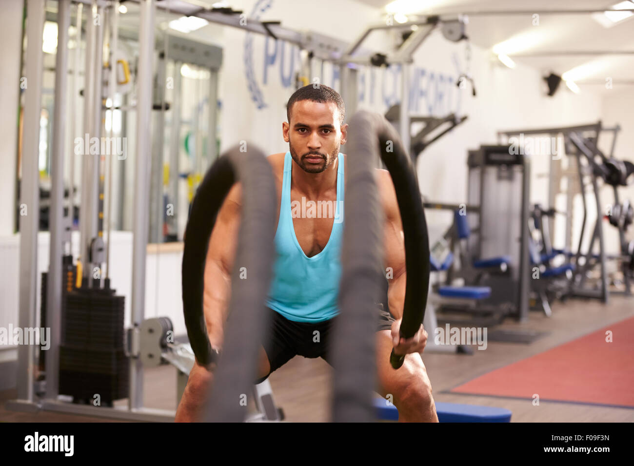 Young man working out with battle ropes at a gym Stock Photo - Alamy