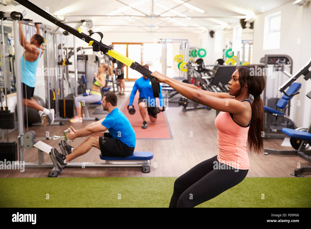 People working out on fitness equipment at a busy gym Stock Photo - Alamy