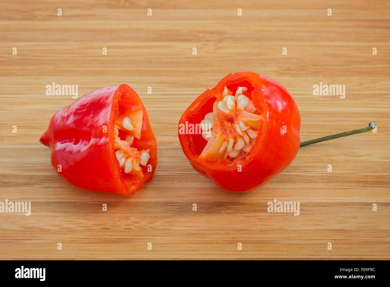 Close-up of a ripe red habanero chili cut in half on a wooden chopping ...
