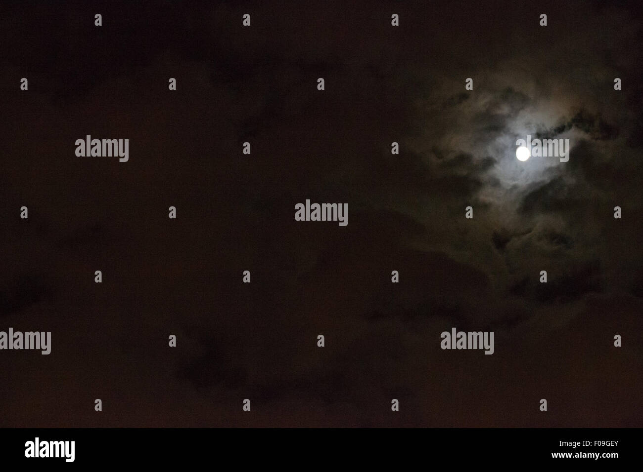 Night picture of the moon showing in a gap between clouds Stock Photo ...