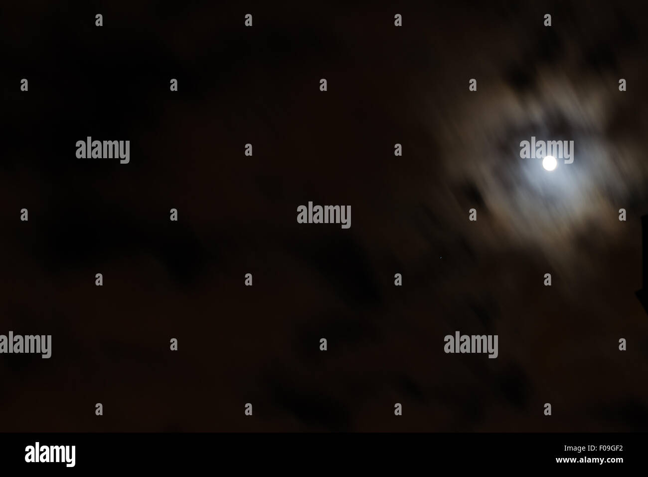 Night picture of the moon showing in a gap between clouds Stock Photo ...