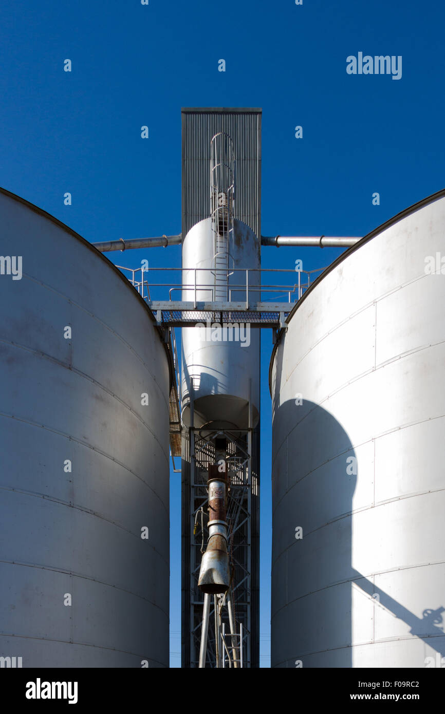 Shot taken of two silos and their drop tube inbetween.against blue sky ...