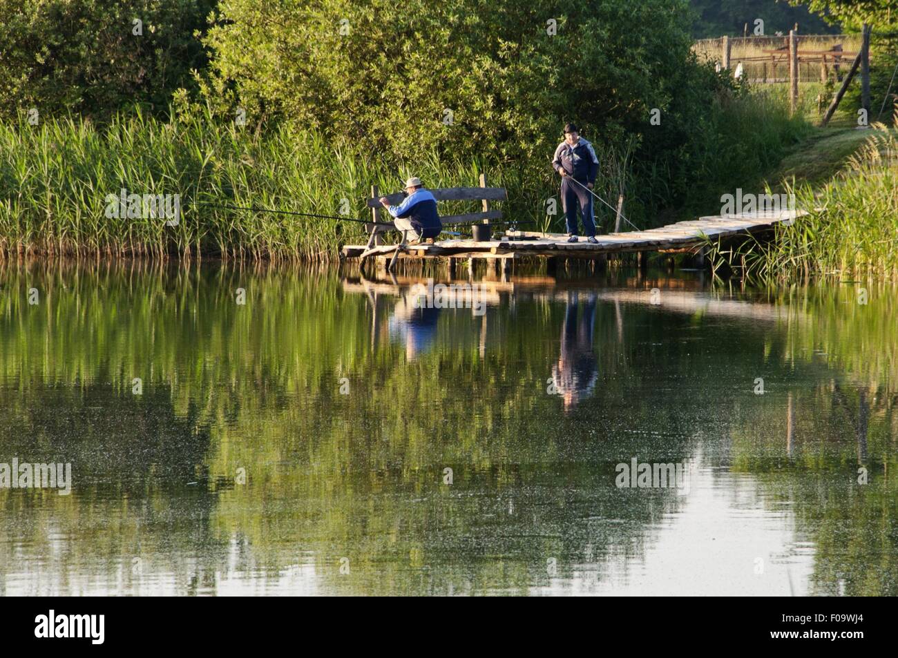 Two men fishing on jetty of Masurian Lake District, Mikolajki, Warmia ...