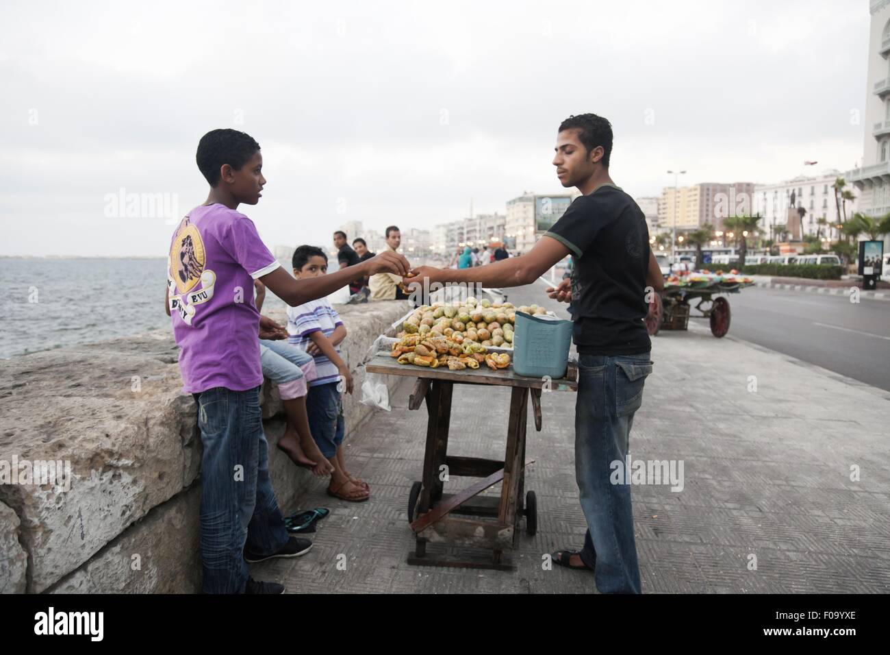 Fruit vendor selling fruit to a boy on the corniche of Alexandria ...