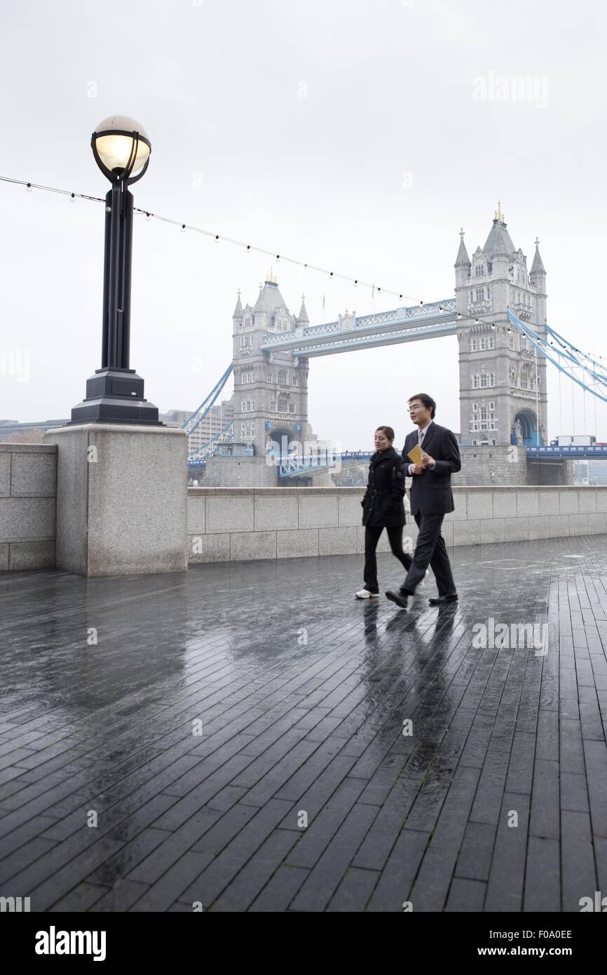 Man and woman walking in rain on Tower bridge, London Stock Photo - Alamy