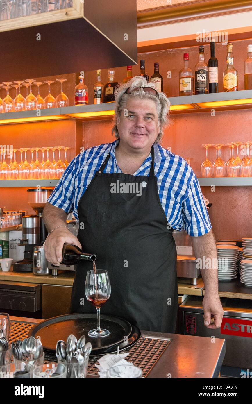 Portrait of Christoph Elbert pouring wine in glass at kitchen, Linden ...