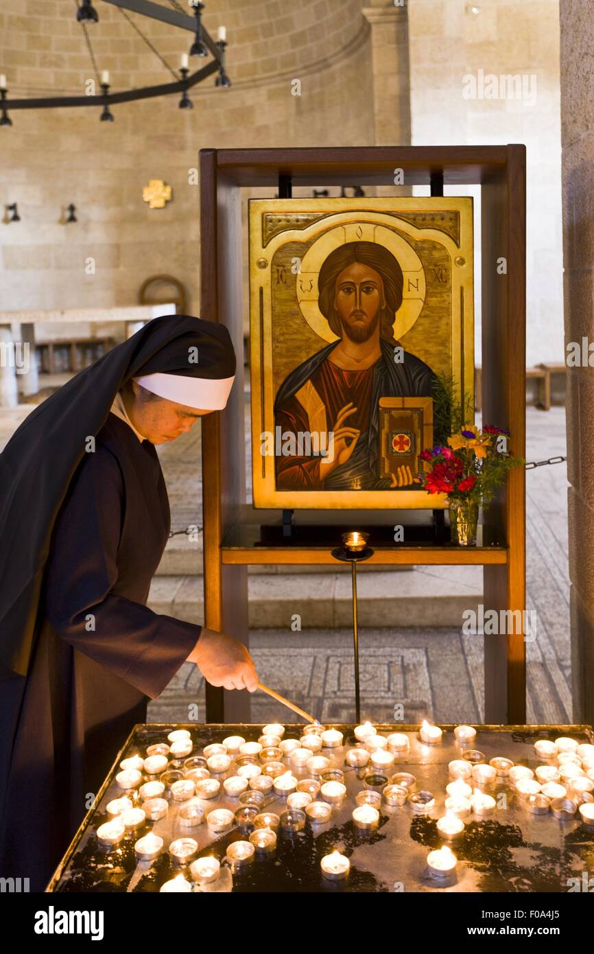 Nun lighting candles in Church in front of Jesus photo frame, Tabgha ...