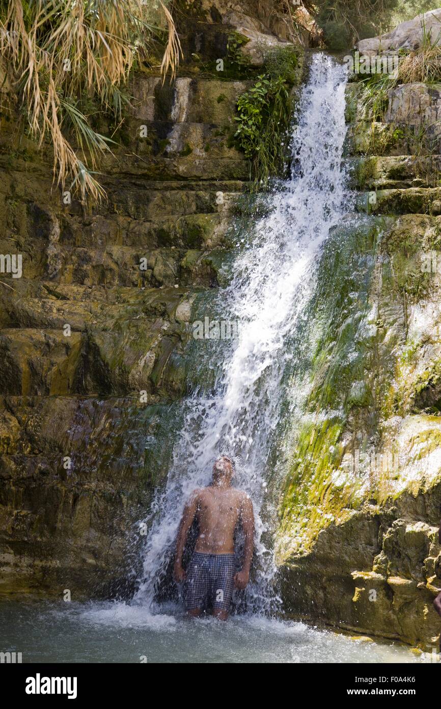 Man standing under waterfall near Dead Sea in Ein Gedi National Park ...