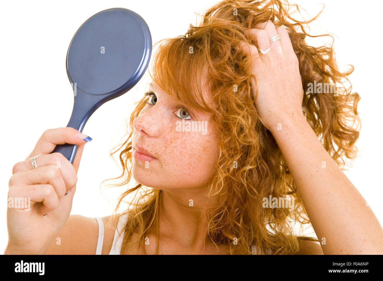 Young redhaired woman checking her hair in a hand mirror Stock Photo ...