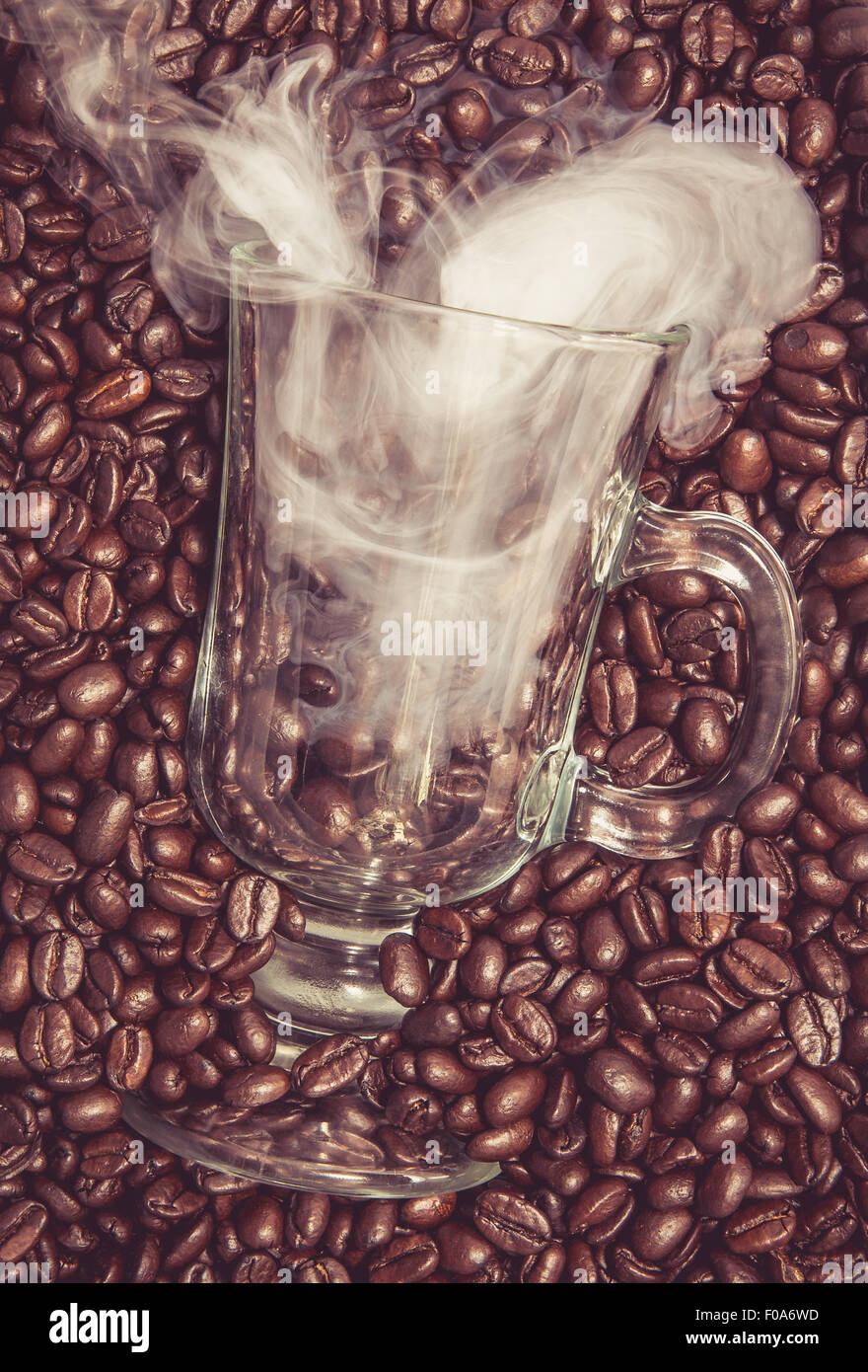 Irish coffee glass stuck in fresh coffee beans. Smoke is coming out of ...