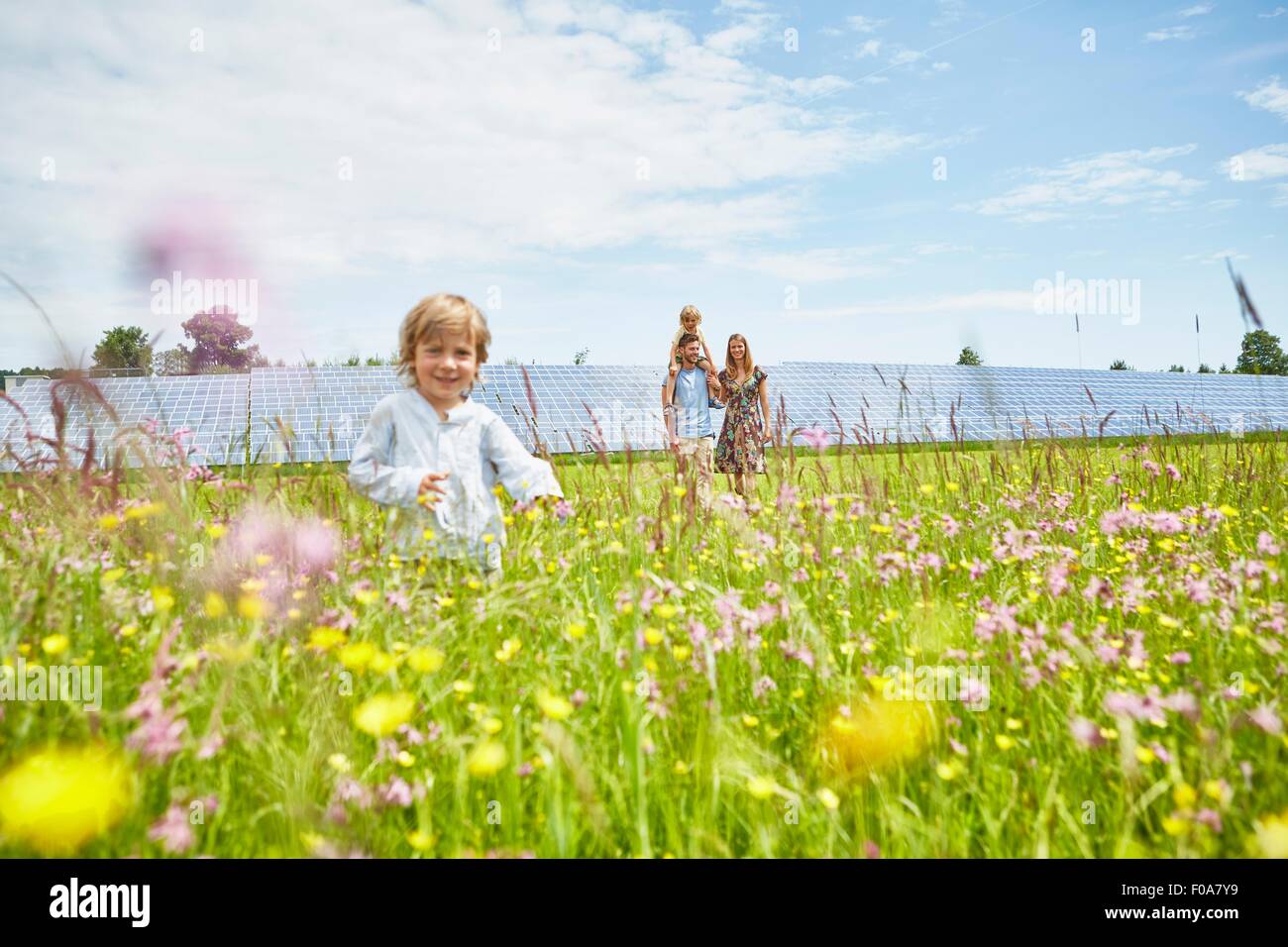 Young boy running through field, mother, father and brother following ...
