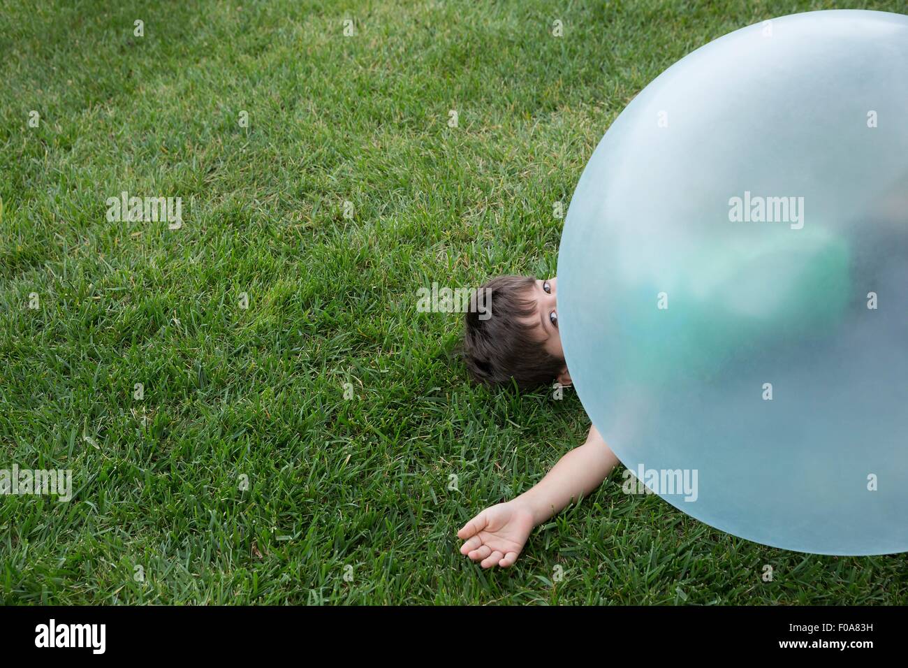 Young boy lying under large inflatable ball Stock Photo - Alamy