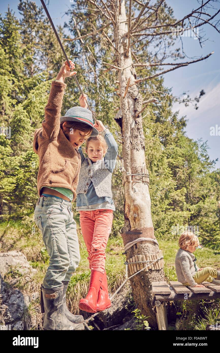 Two children walking across single rope bridge Stock Photo - Alamy