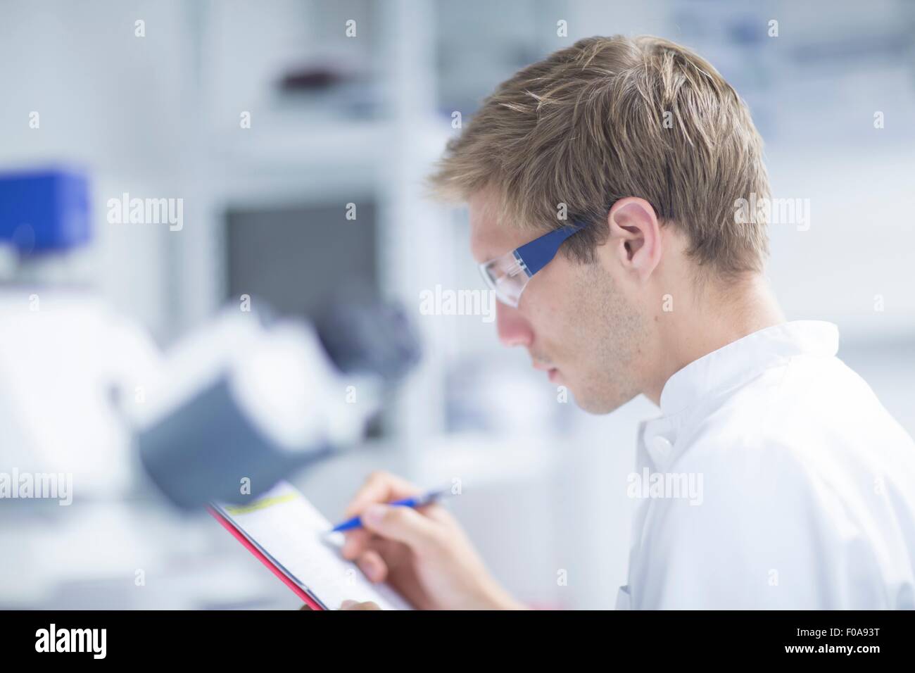 Male scientist writing in notebook in laboratory Stock Photo - Alamy
