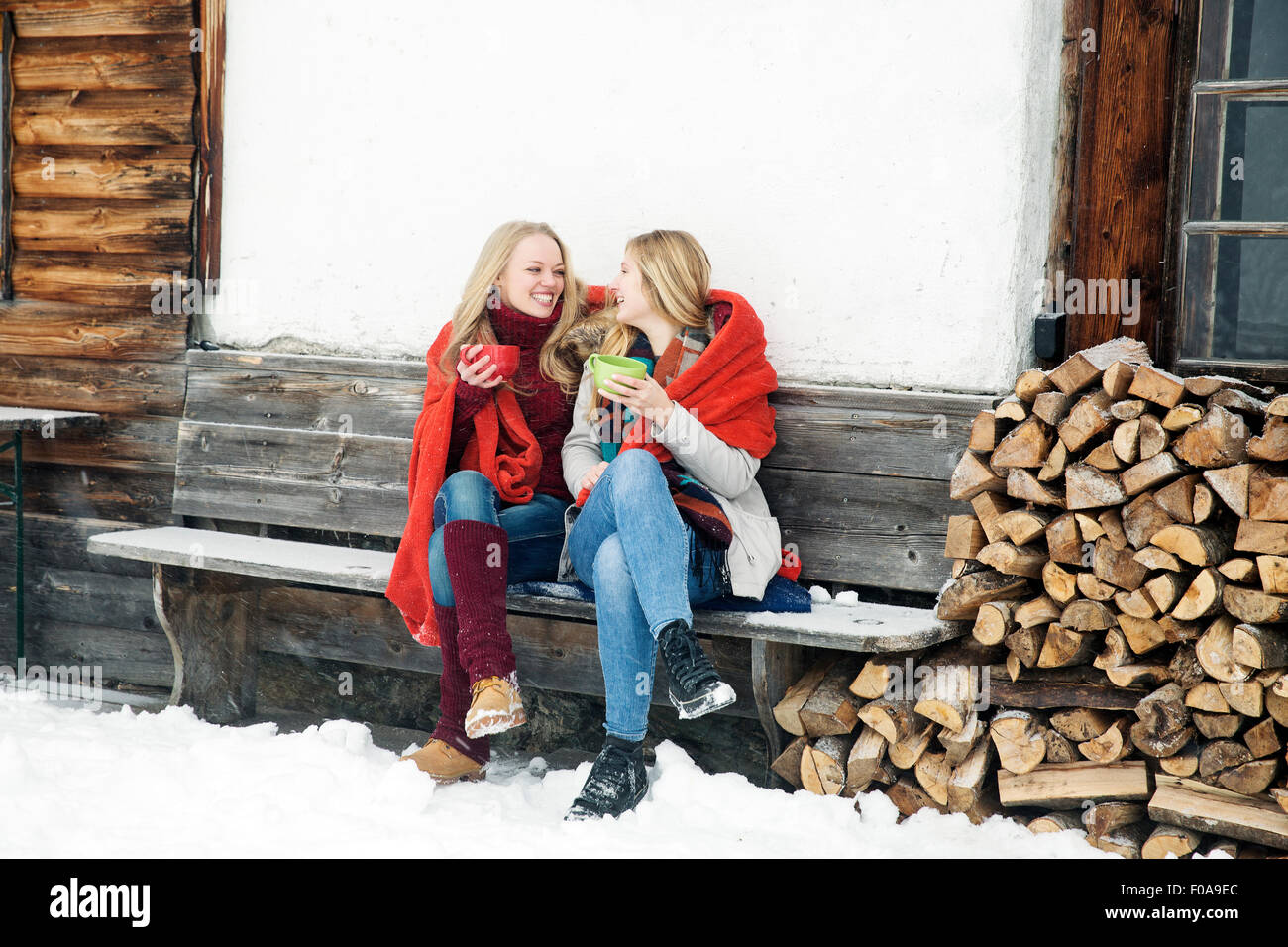 Two young female friends drinking coffee outside wooden cabin Stock ...