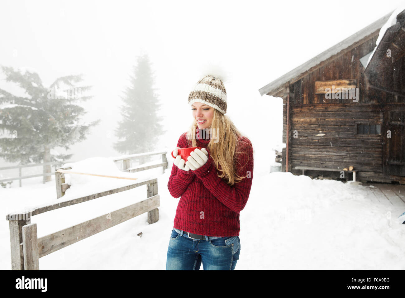 Young woman drinking coffee in snow outside cabin Stock Photo - Alamy