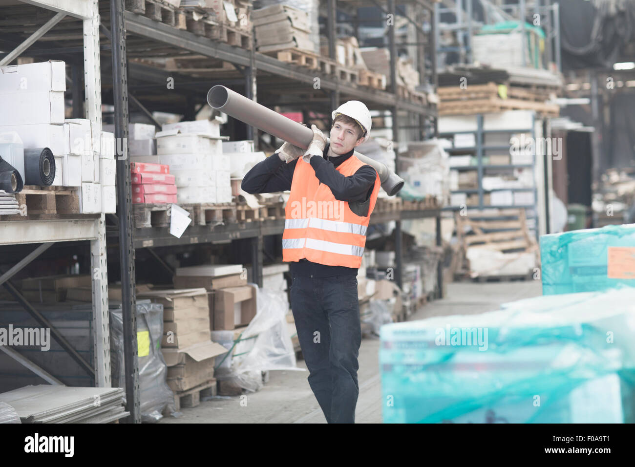 Young male warehouse worker carrying industrial pipe on shoulder Stock ...