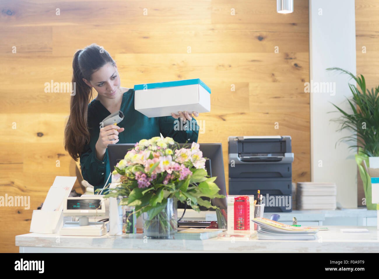 Female sales assistant using barcode reader on shoe box in shoe shop ...