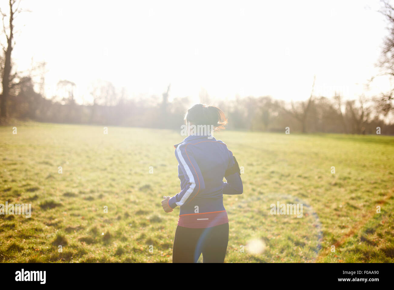 Rear view of mature female runner running in field Stock Photo - Alamy